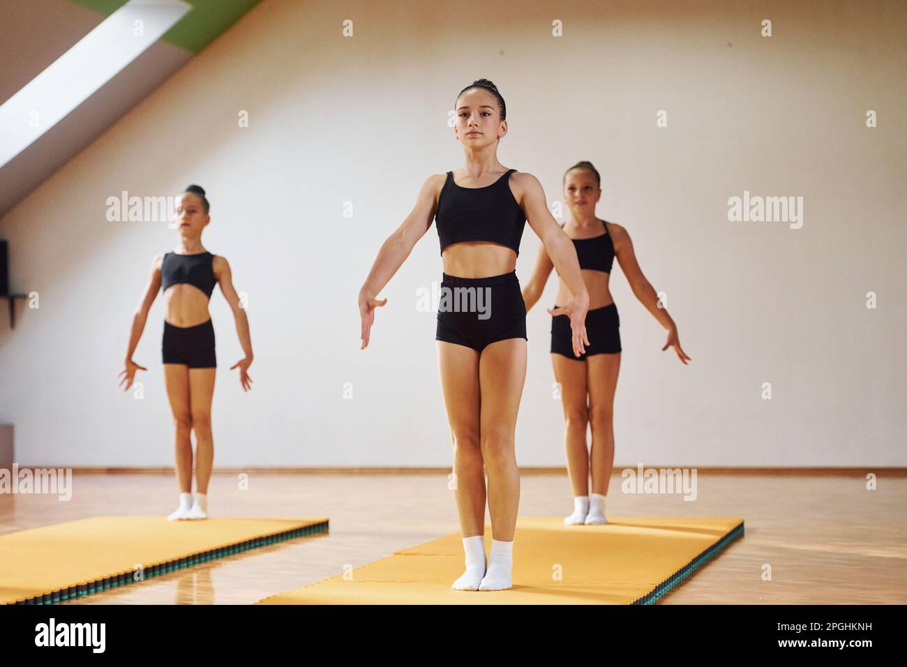 Daily routine. Group of female kids practicing athletic exercises ...