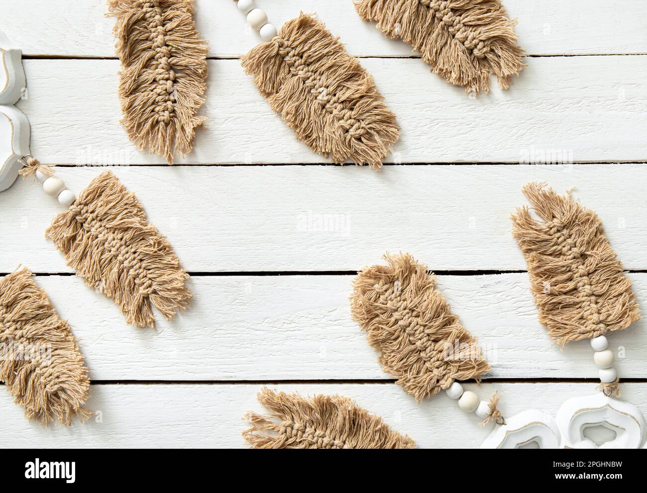 Light brown leaf or feather shape macrame hanging against white wood ...