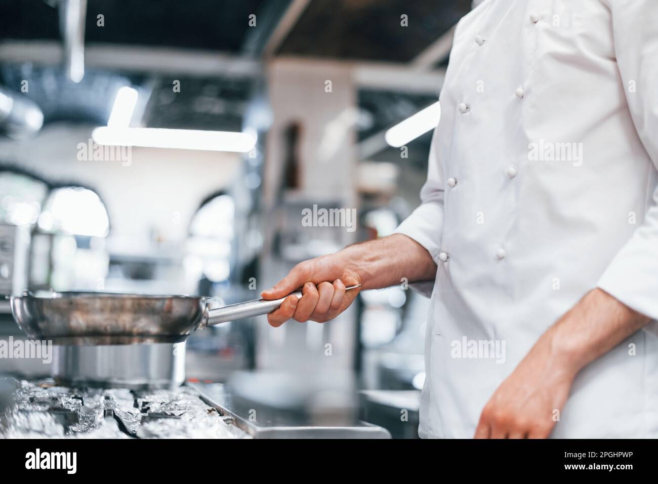 Making delicious product. Chef in white uniform cooking food at kitchen ...