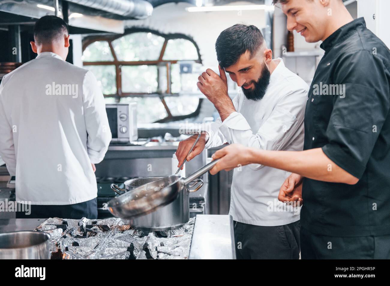 People in white uniform cooking food at kitchen together. Busy day at ...