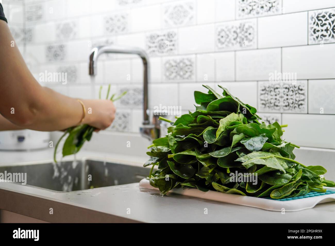Woman washing spinach in the kitchen Stock Photo - Alamy