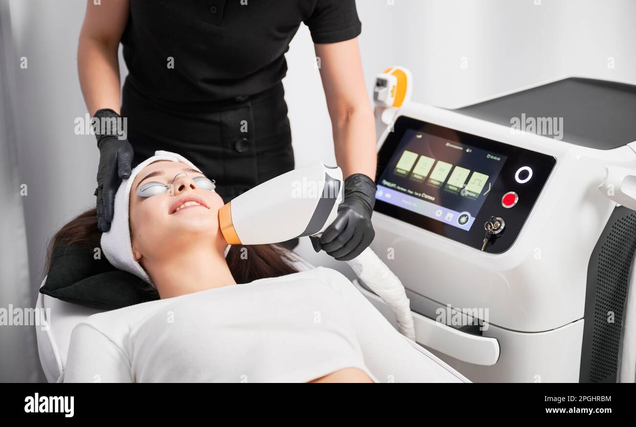 Female patient in safety glasses lying near cosmetology equipment and ...
