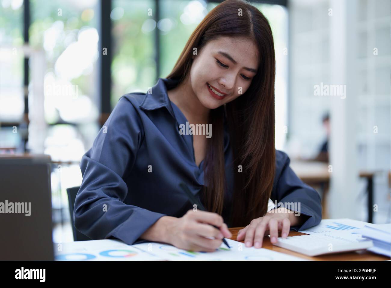 A portrait of an Asian female accountant with a smiling face sits and ...