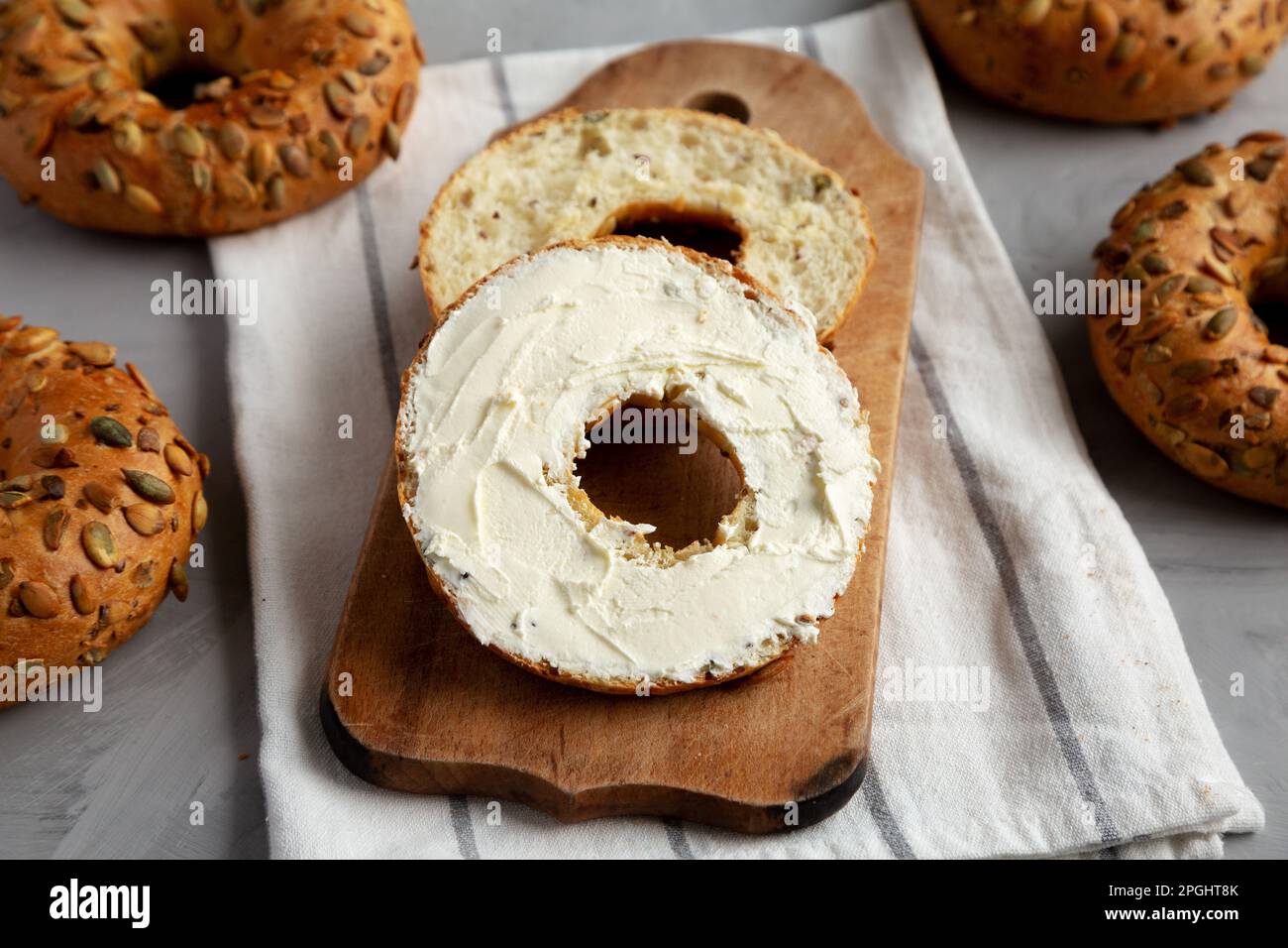 Homemade Whole Grain Bagel with Cream Cheese on a rustic wooden board ...