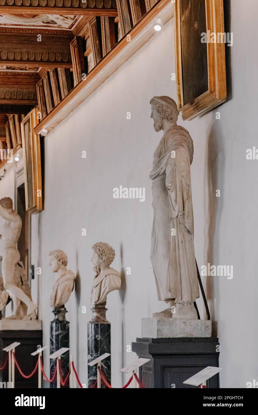 A vertical, close-up shot of two ancient stone statues situated indoors ...