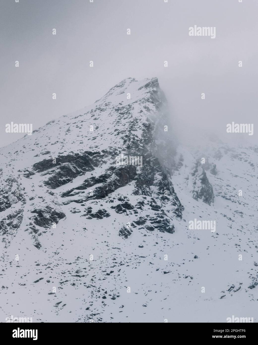 A scenic winter landscape featuring snow-capped mountain peaks emerging ...