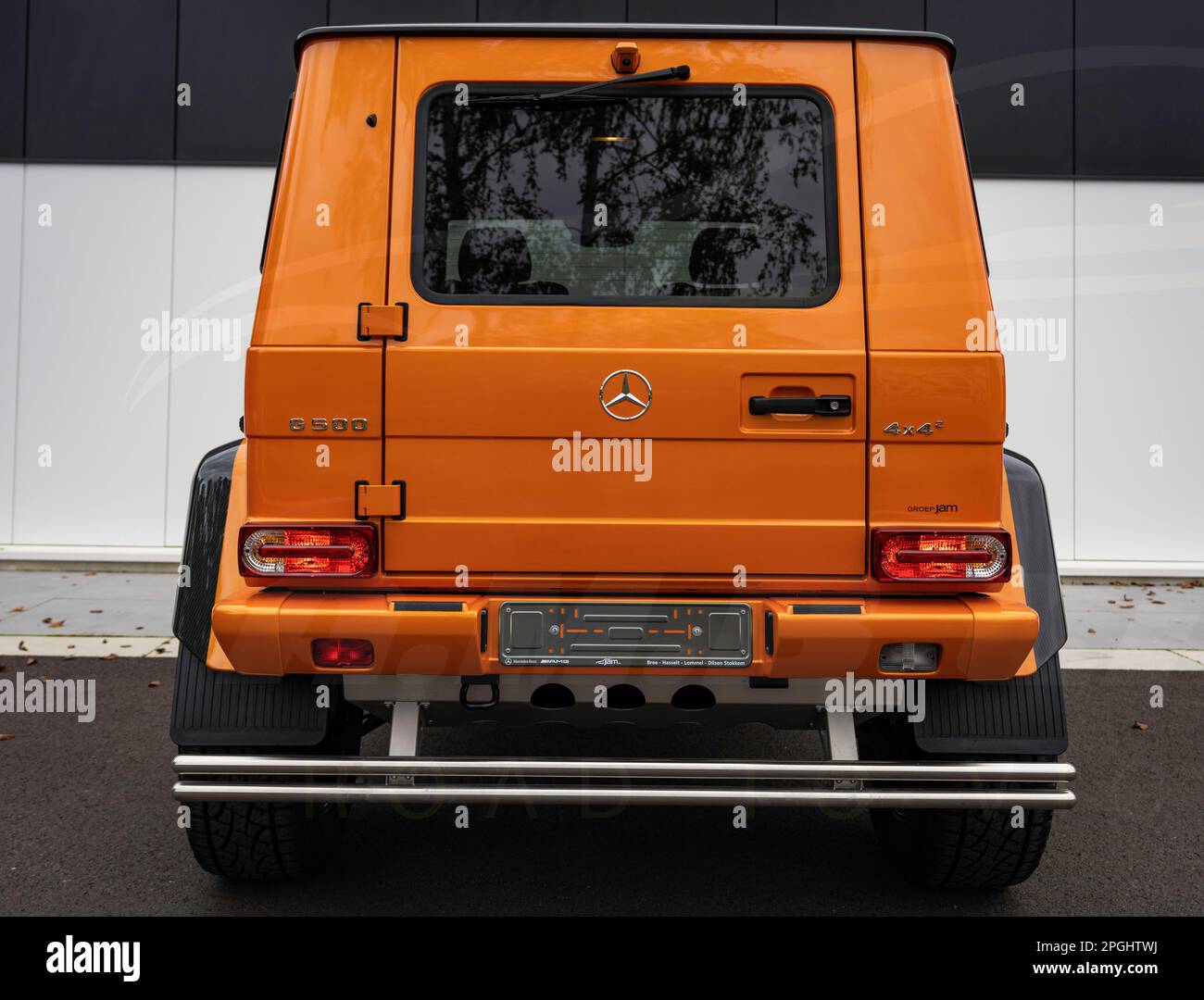 A rear view of a bright orange Mercedes-Benz G-Class SUV parked in a ...