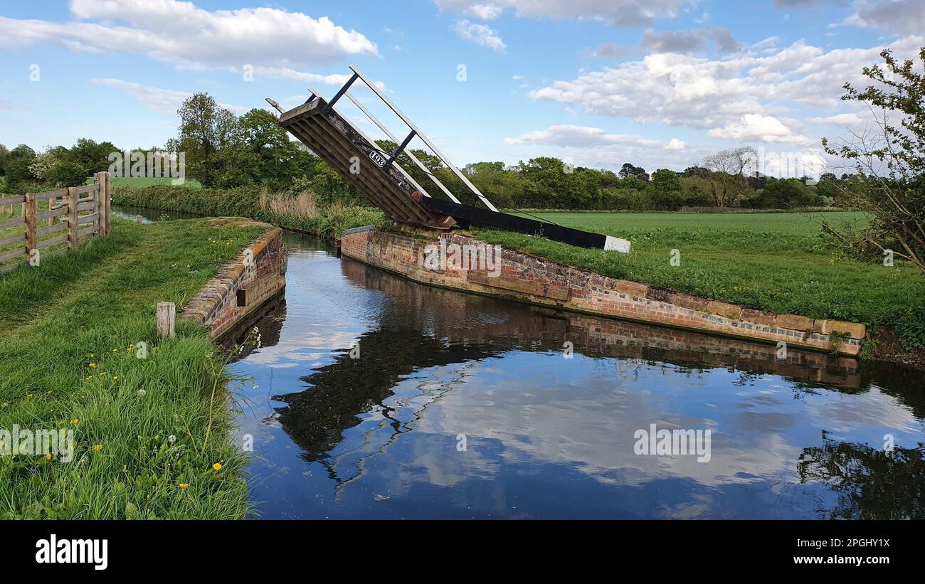 A countryside landscape with a small raised bridge over a narrow canal ...
