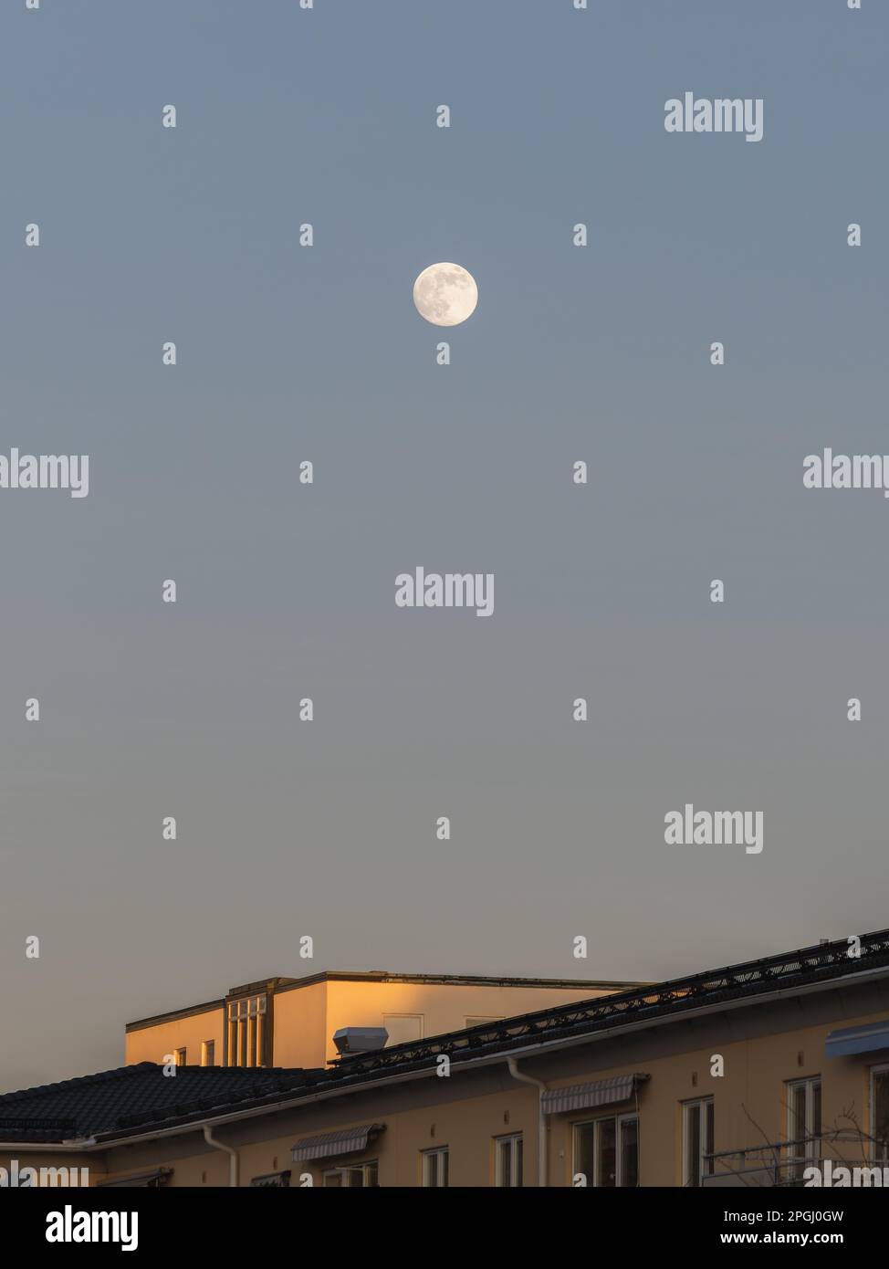 A night sky view featuring the full moon rising over an urban skyline ...