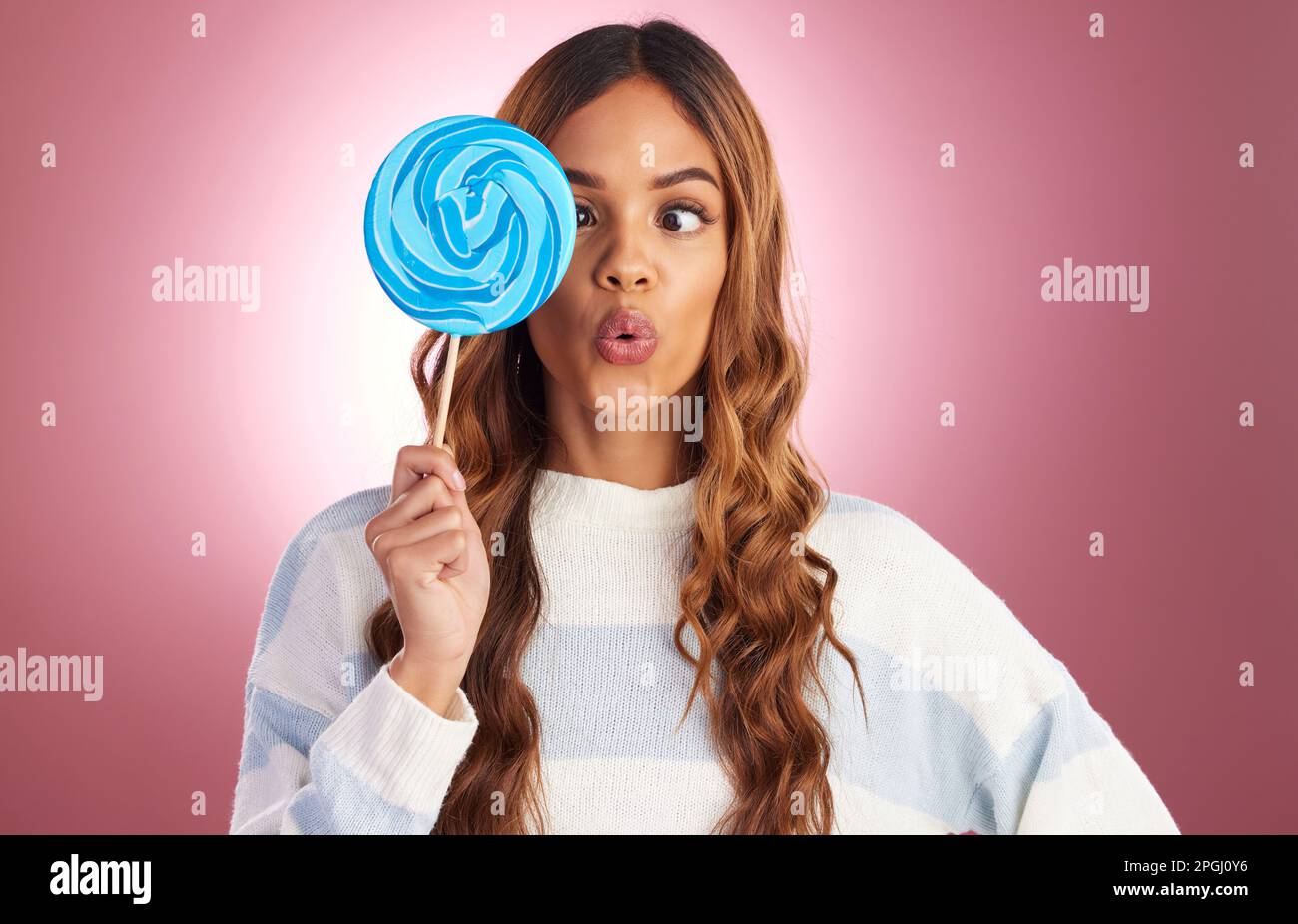 Portrait, funny face and lollipop with a woman on a pink background in ...