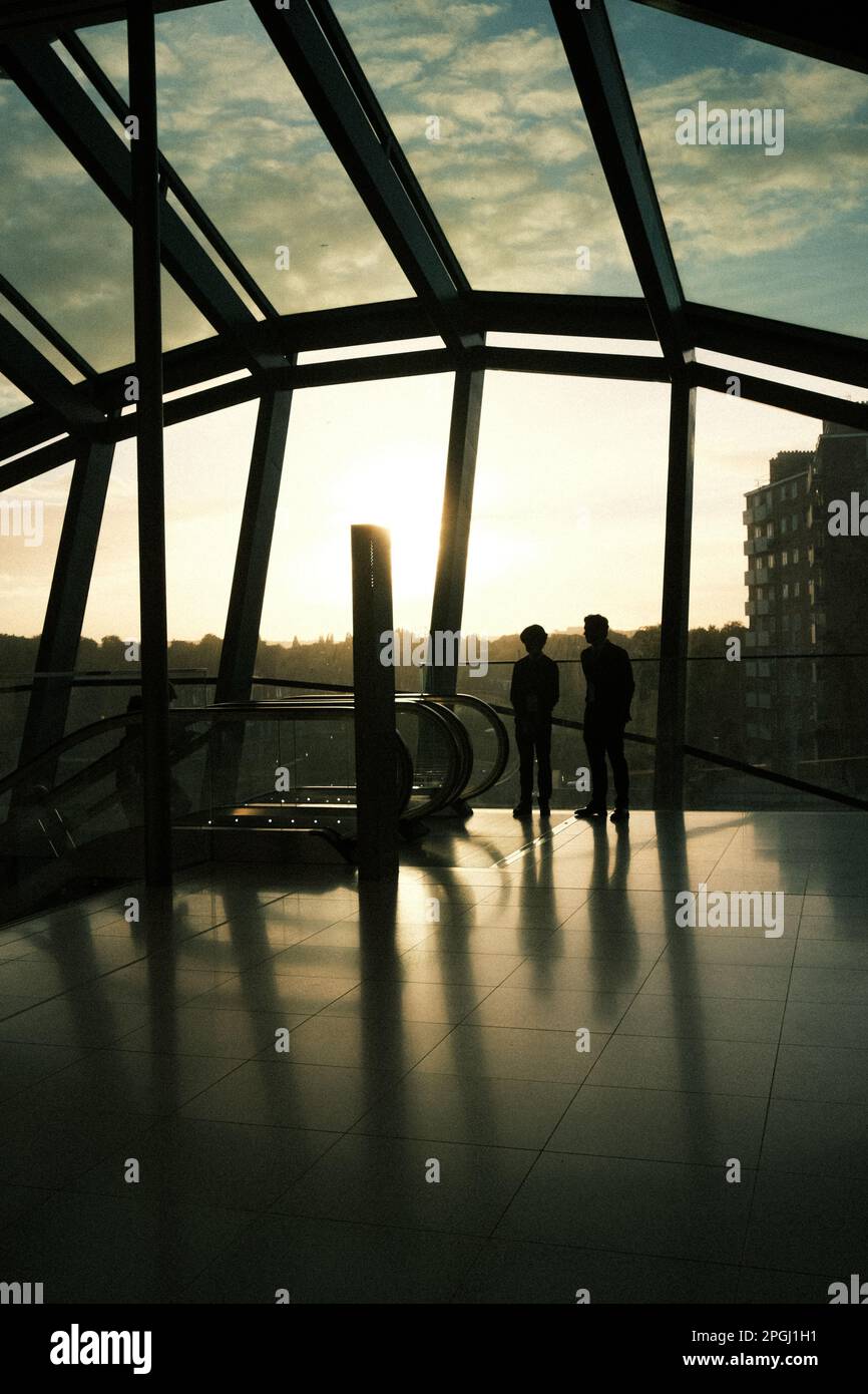 Two people standing side by side and looking outside, enjoying the view ...