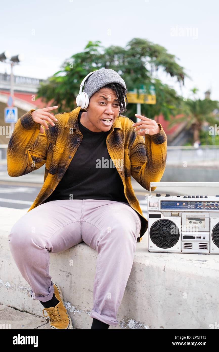Rapper woman making rhymes outdoors with music that is heard from her ...