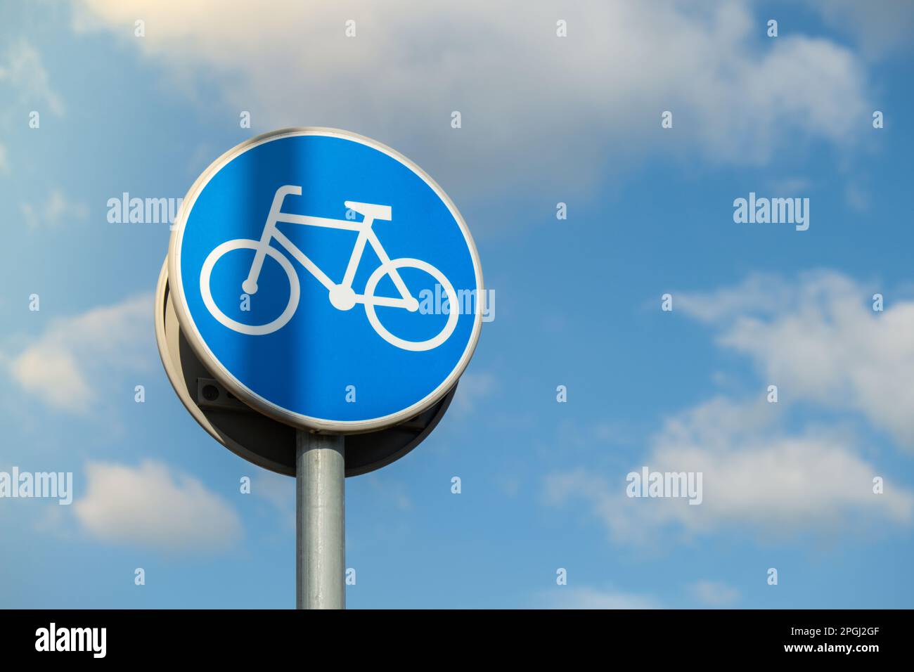 Round road sign depicting white bicycle on blue background, meaning mandatory bike path for ...