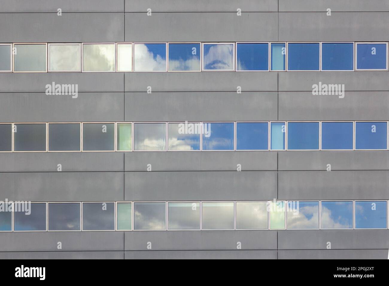Blue skies and clouds visible reflected in the windows of a nondescript ...