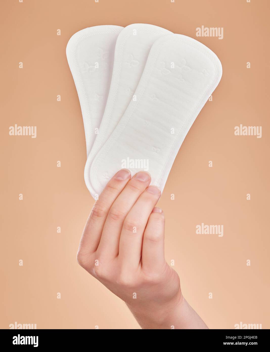 Hand, sanitary pads and period with a woman in studio on a brown ...
