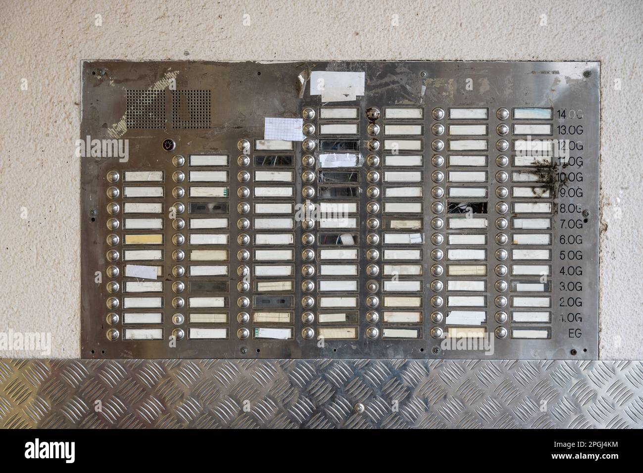 Many door bells without names on a dirty metal plate at the entrance of ...