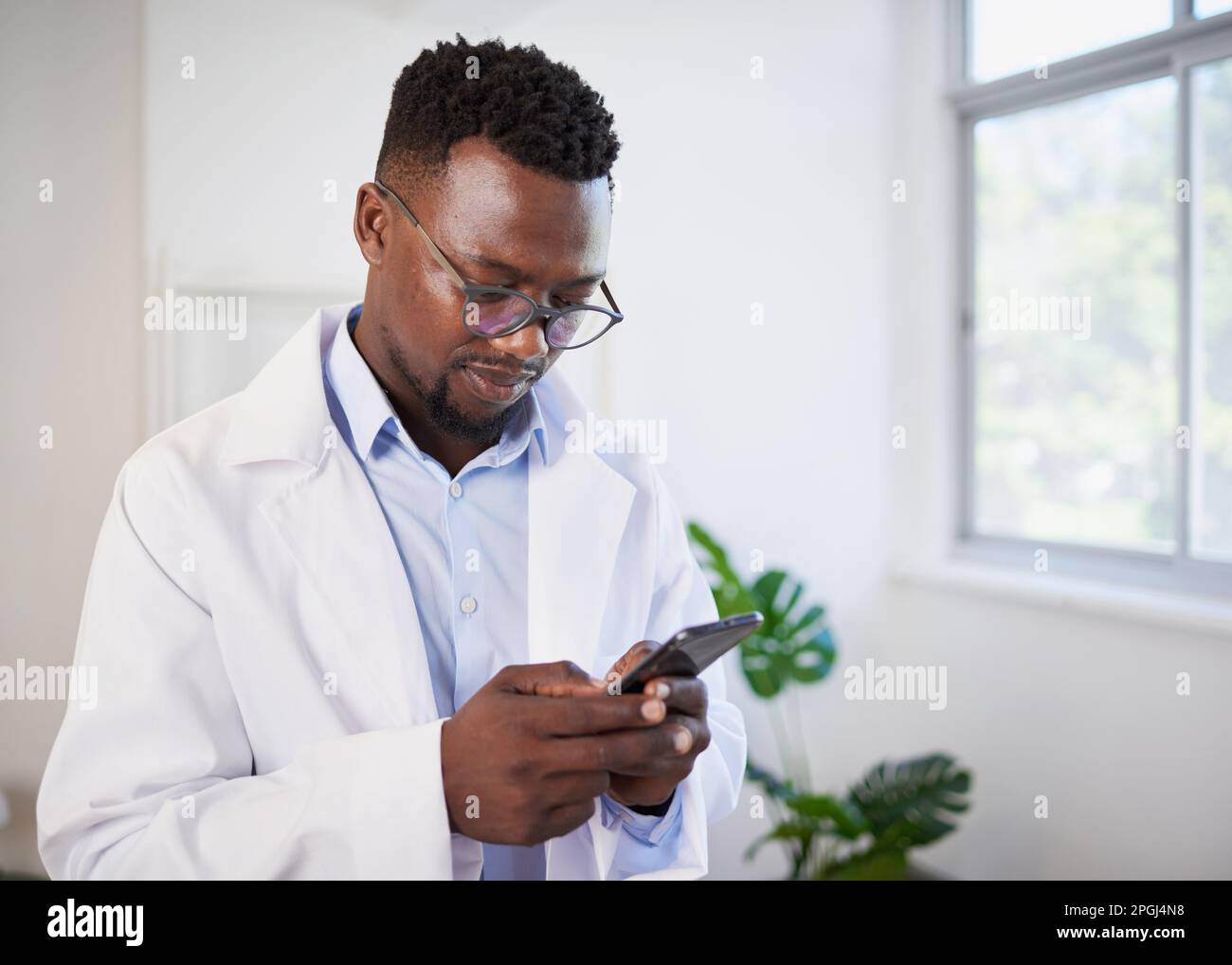 Close up of Black doctor texting on cellphone in modern clinic office ...