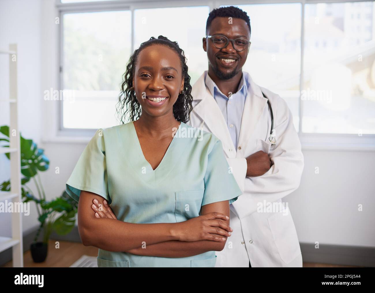 Portrait of two Black doctors, man and woman arms folded posing in ...
