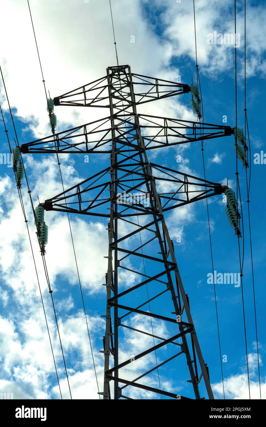High voltage power lines under a bright blue sky with scattered clouds ...