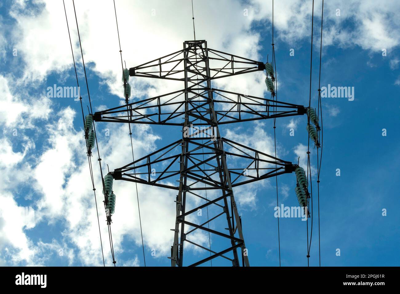 High voltage power lines under a bright blue sky with scattered clouds ...