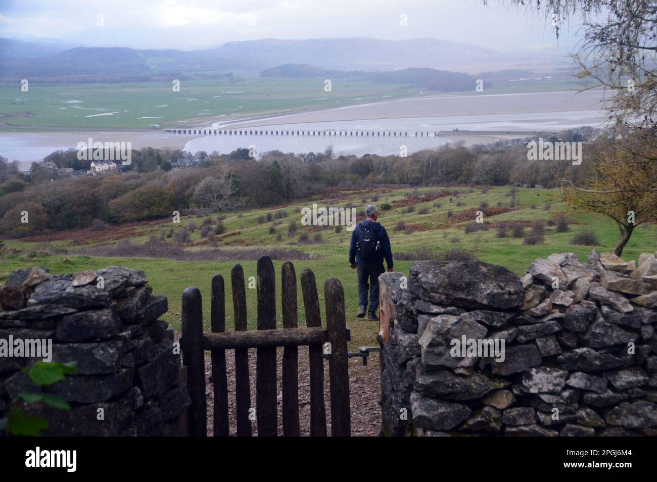 Lone Man Walking Past Wooden Gate in Stone Wall leading to down to Red ...