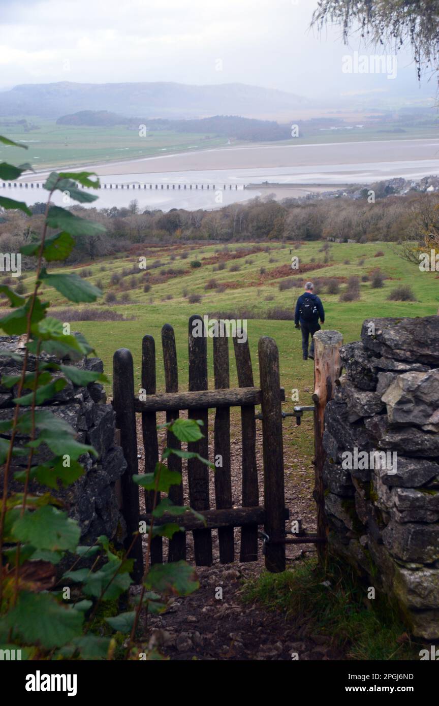 Lone Man Walking Past Wooden Gate in Stone Wall leading to down to Red ...