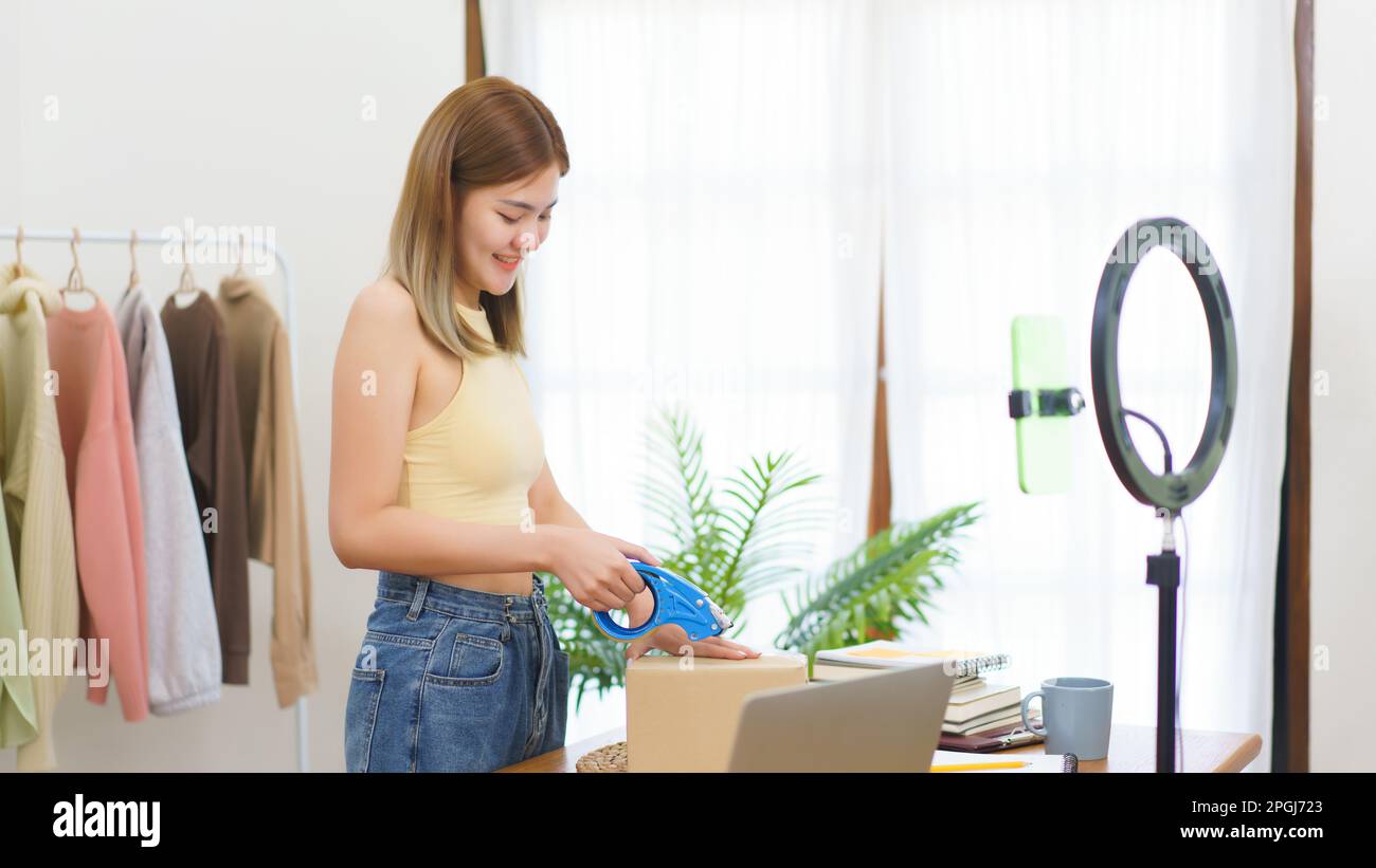 Online merchant concept, Fashion designer packing clothes into parcel ...