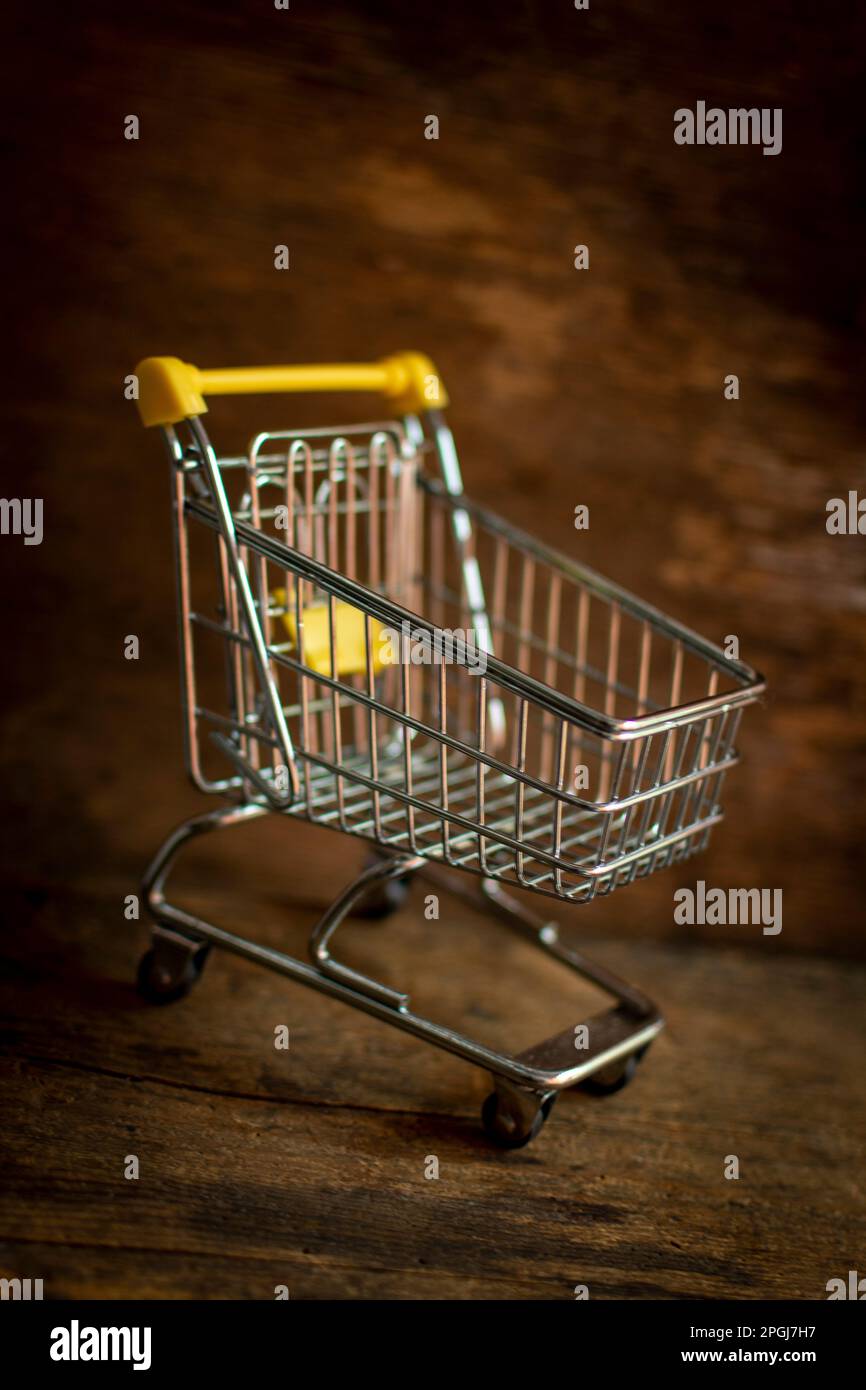 Small shopping cart on a wooden surface with a textured background ...
