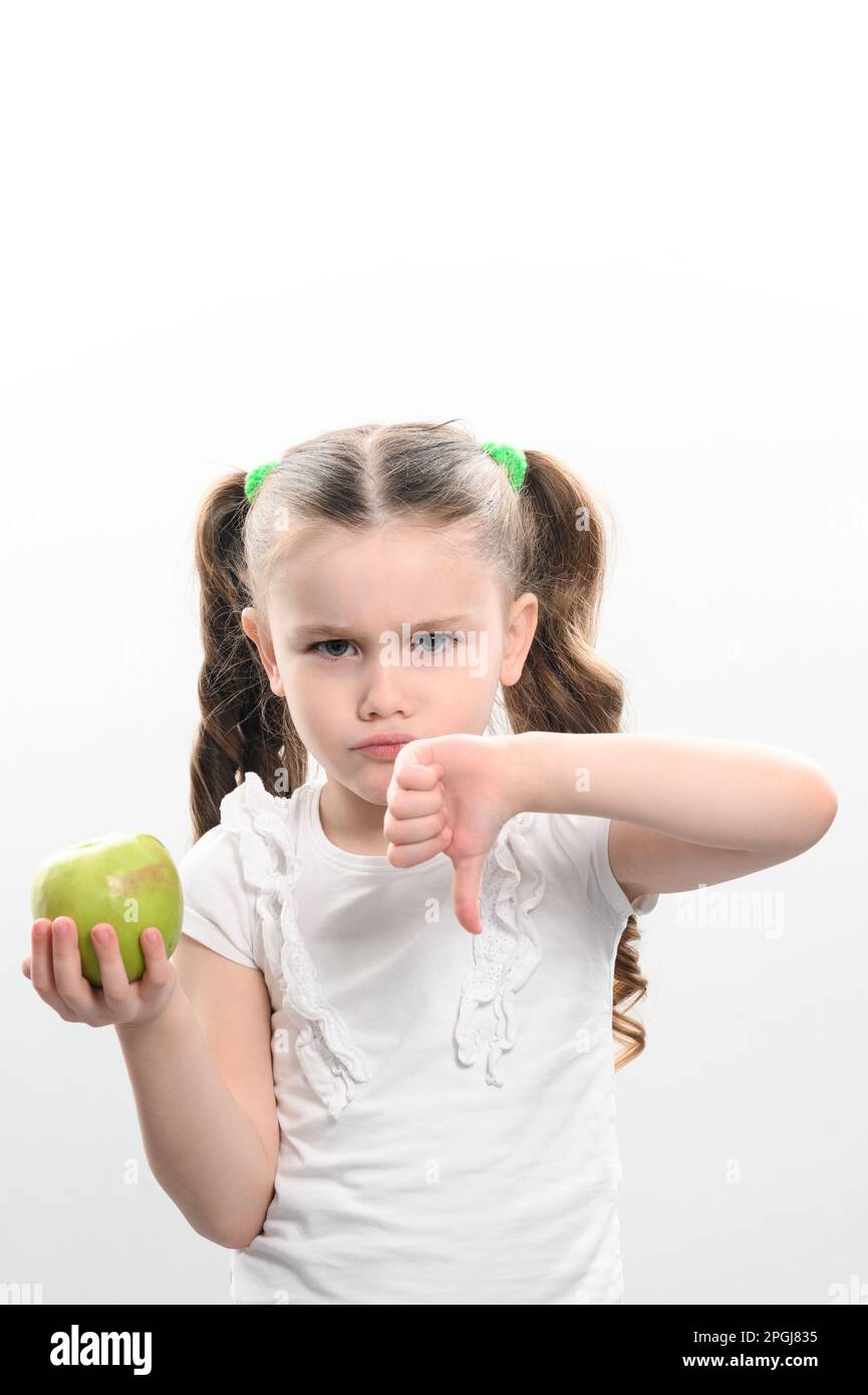 Portrait of a little girl on a white background holding an apple in one ...