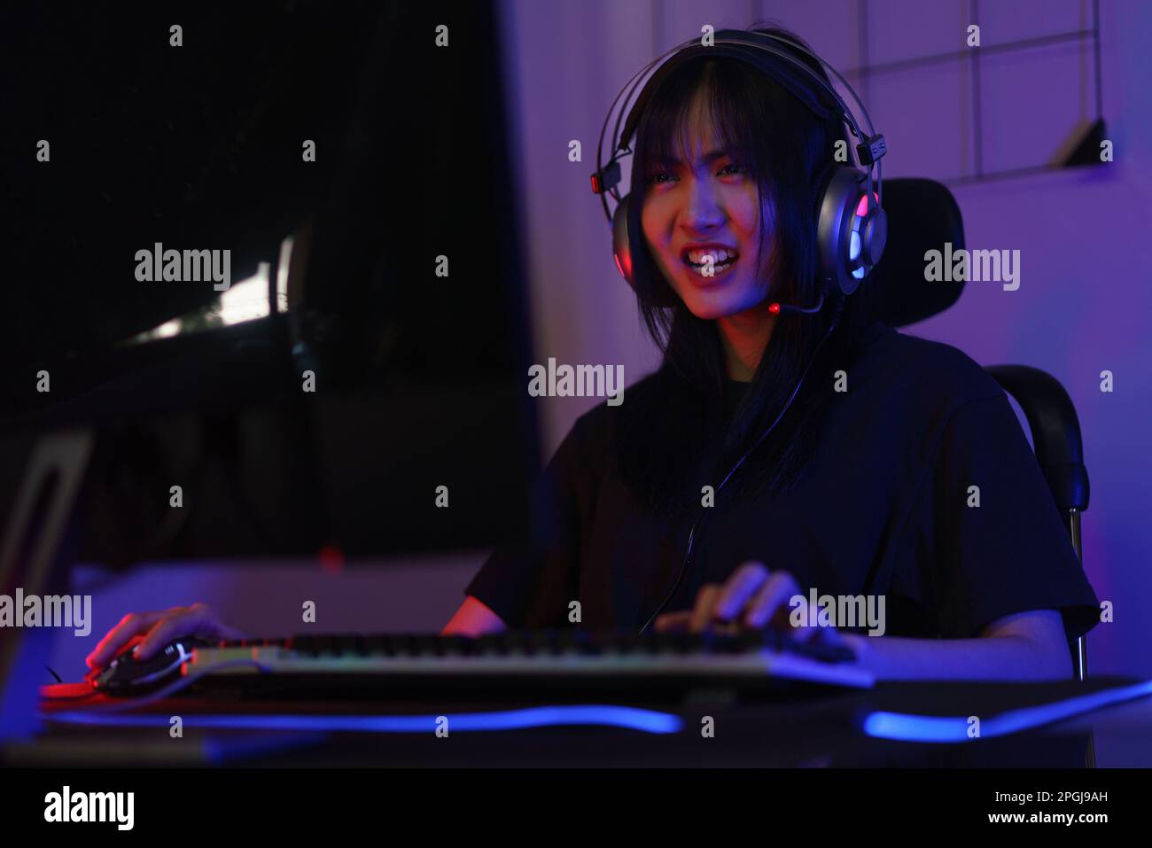 Female cyber hacker gamer in headphone serious face to playing games or hacking programming ...