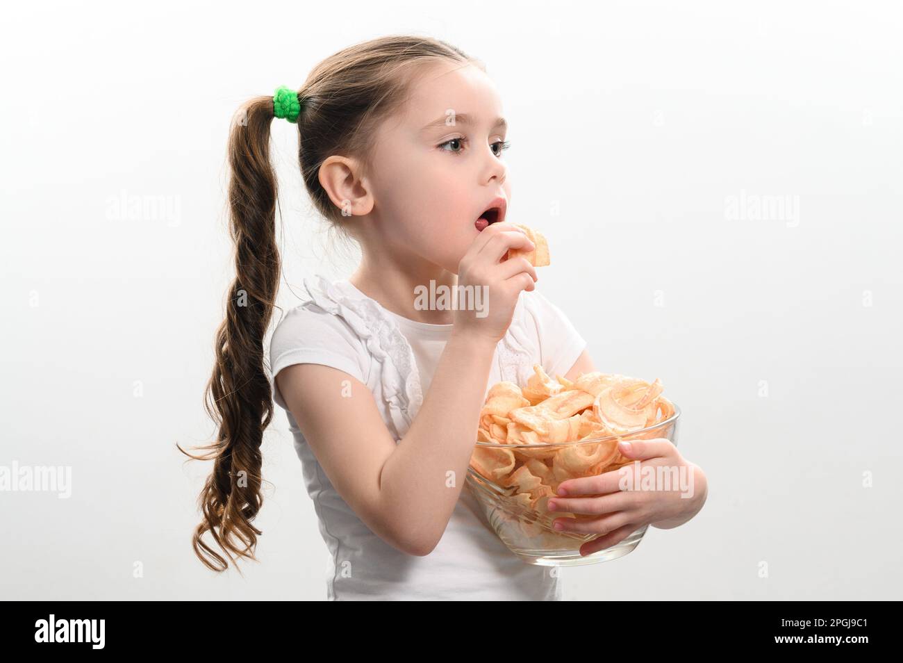 A girl takes chips snacks with lard from a bowl and eats them, portrait ...