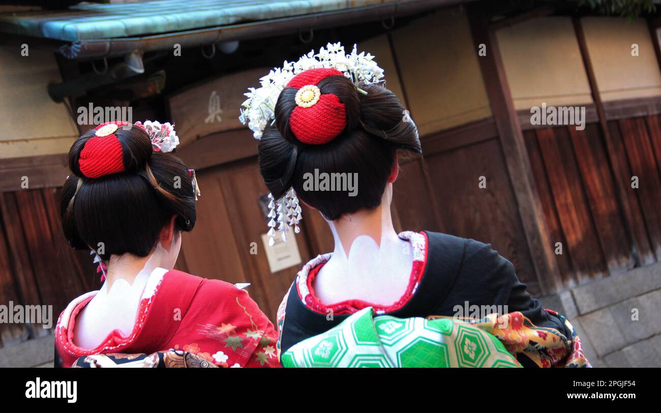 Two Japanese women wearing traditional kimono and ornate makeup while ...