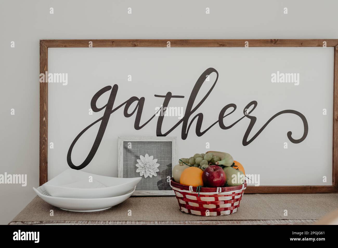 A frame with the writing "gather" next to a plate and fruits isolated ...