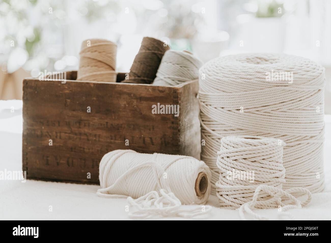 A stack of colorful thread spools in a wooden box set against a white ...