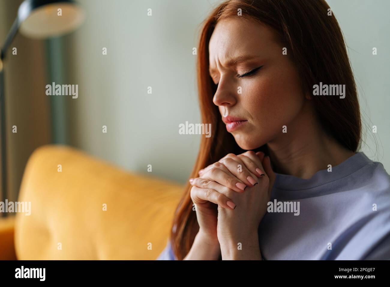 Closeup face of worried anxious young red-haired woman sitting on couch ...