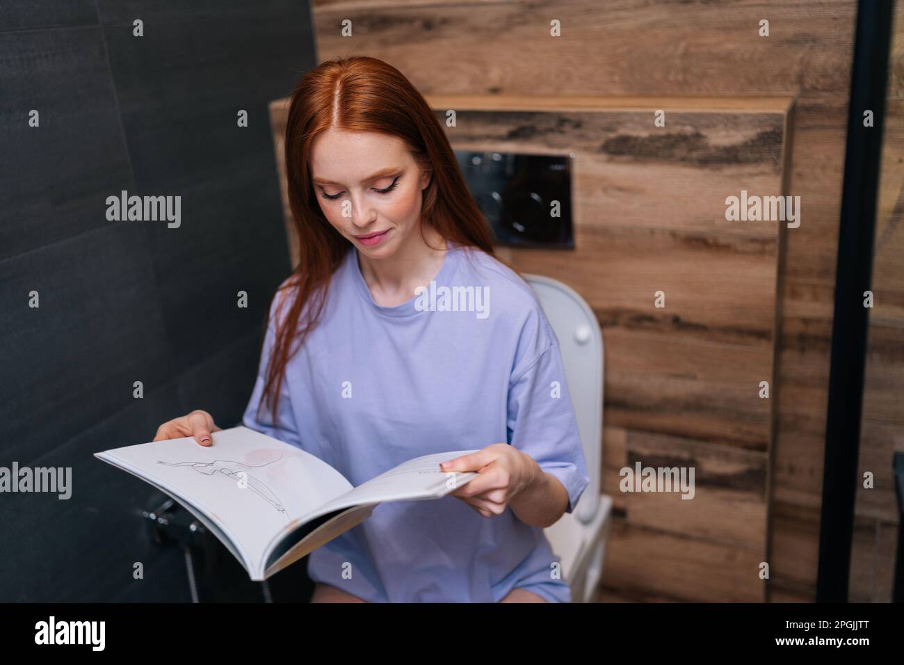 Medium shot of positive young woman reading fashion magazine sitting on ...