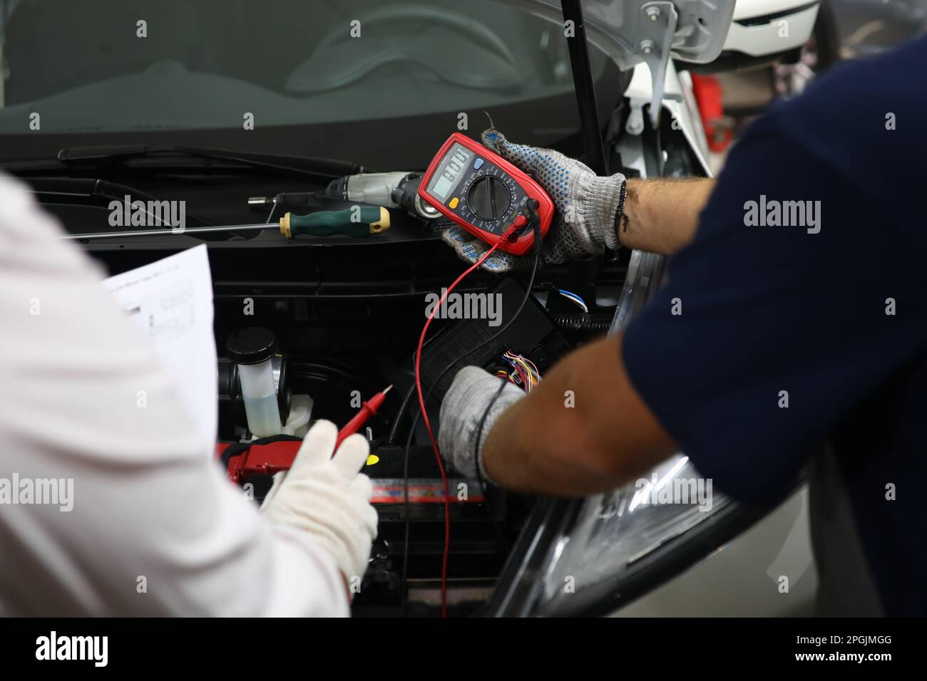 Car repairman checking and testing car battery with digital electronic ...