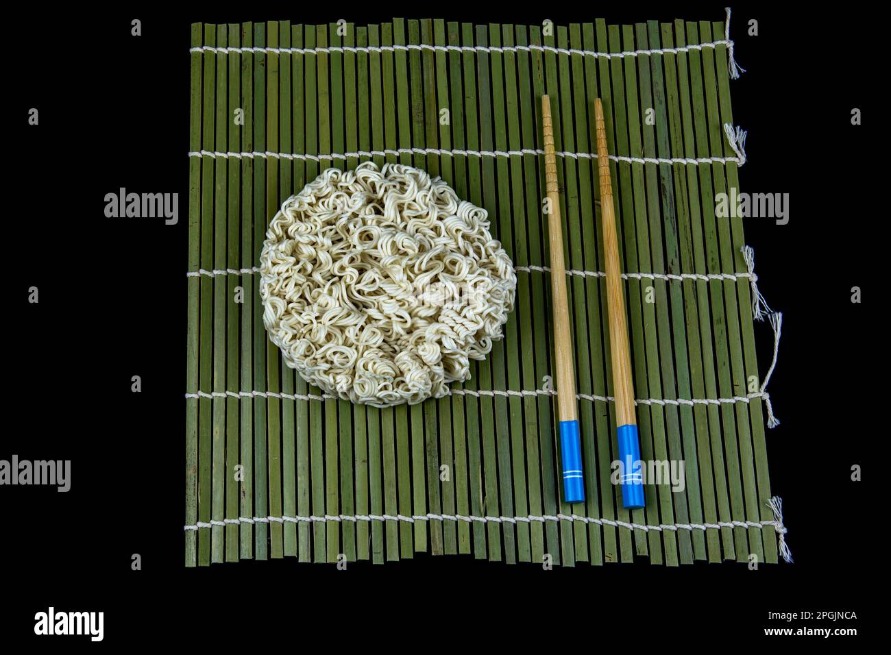 Round block of instant noodles with chopsticks on a bamboo mat on a ...