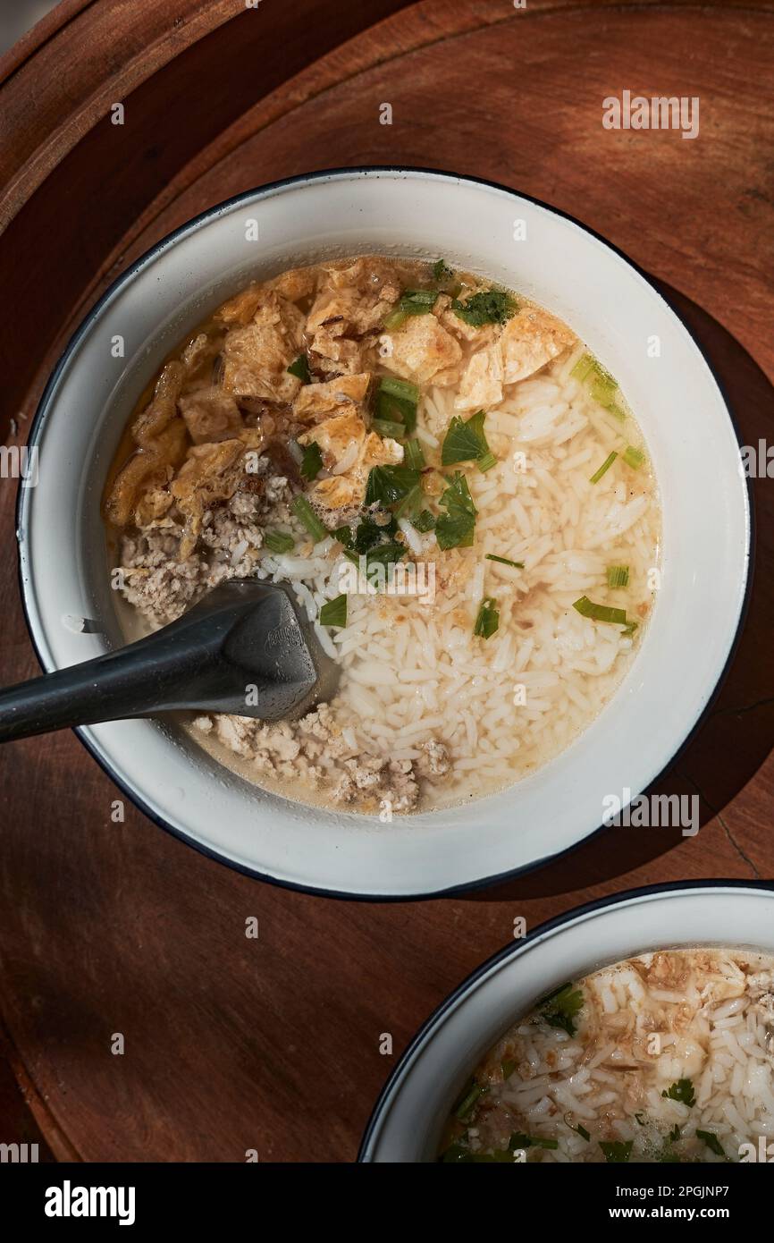 A bowl of congee or porridge with boiled rice in tasty broth with mince ...