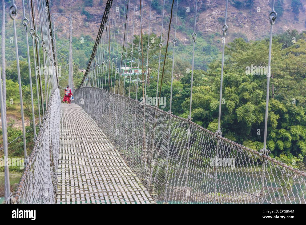 Women crossing the suspension bridge over the Trishuli river in Nepal ...