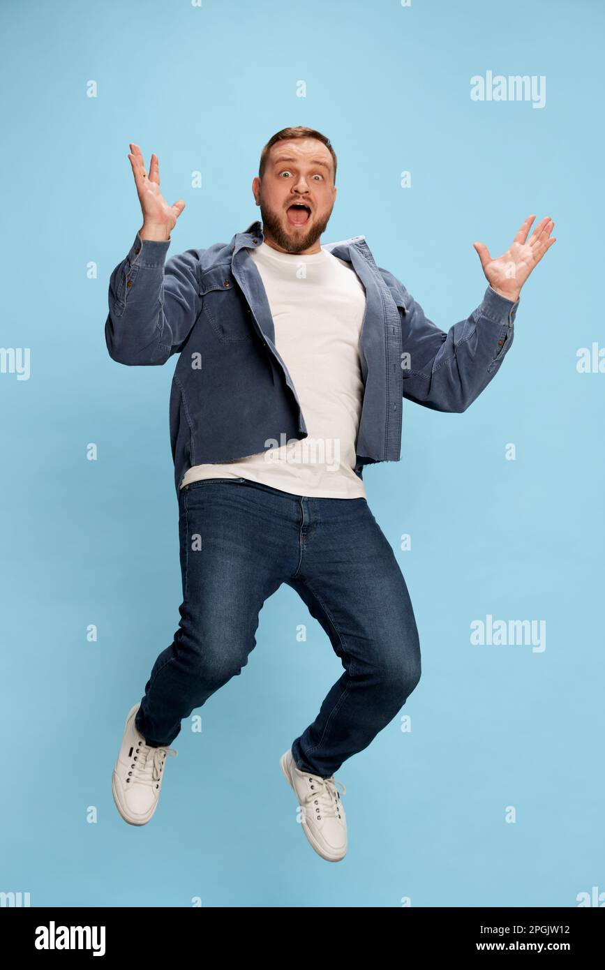 Handsome jumping man wearing white t-short spreading hands and smiling ...