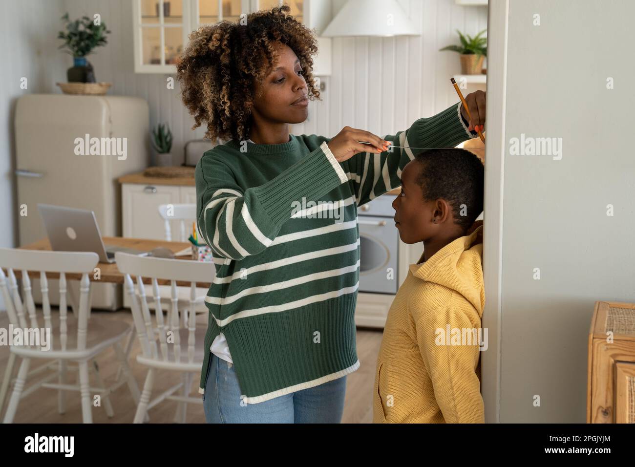 Loving black woman tracking increase measures changes height of kid son ...