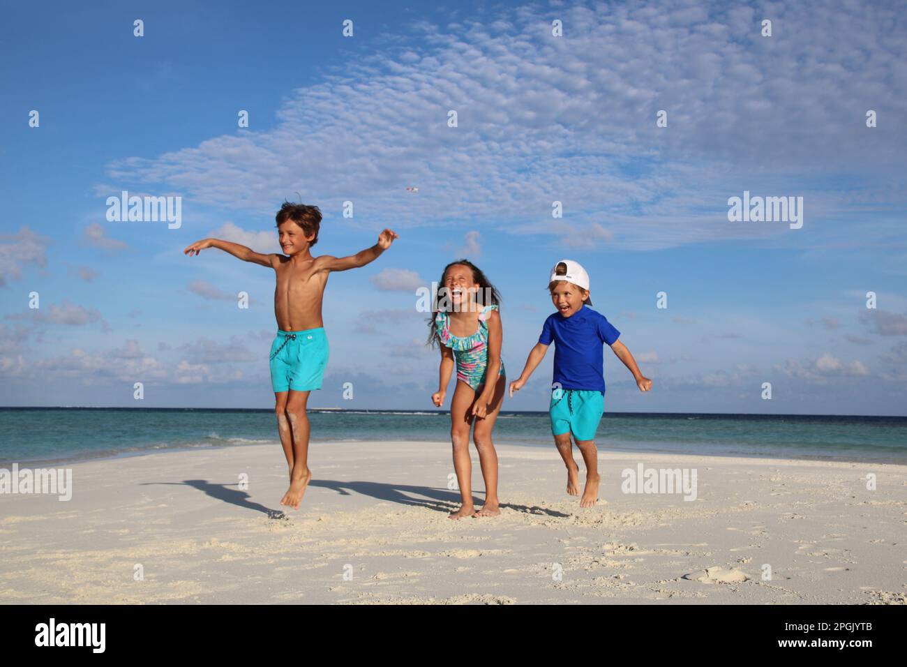Family Holiday, children jumping and laughing on the beach on island, 2 ...