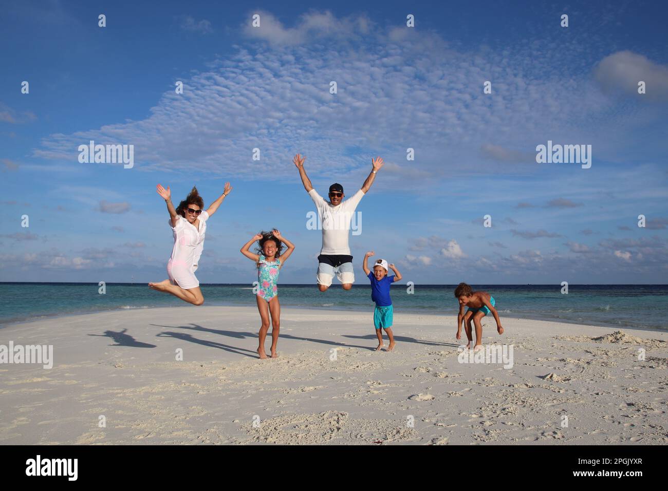 Family jumping and having fun on beach in the Maldives, Indian Ocean ...