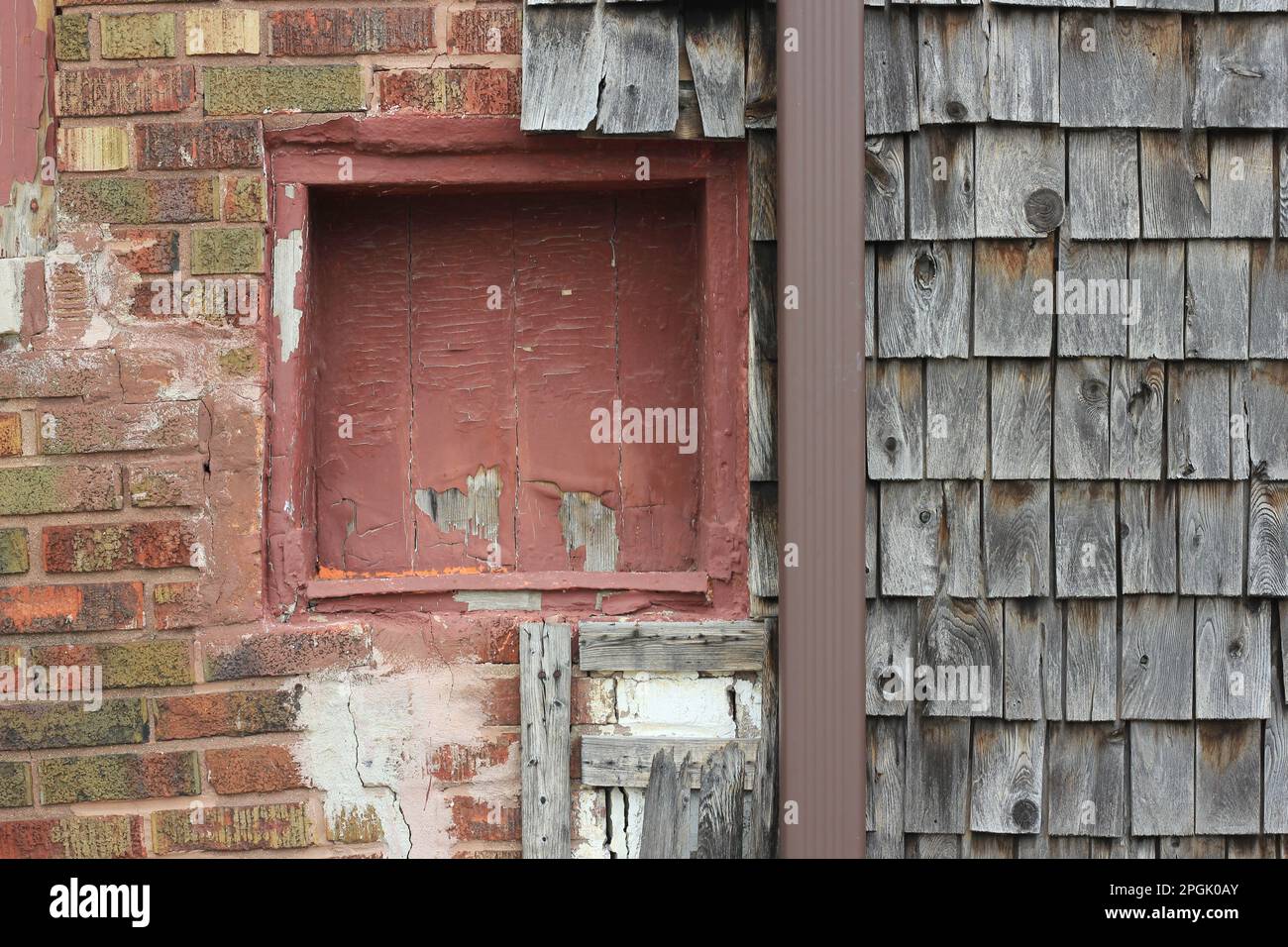 An old worn and weathered brick building blocked with plywood infill ...