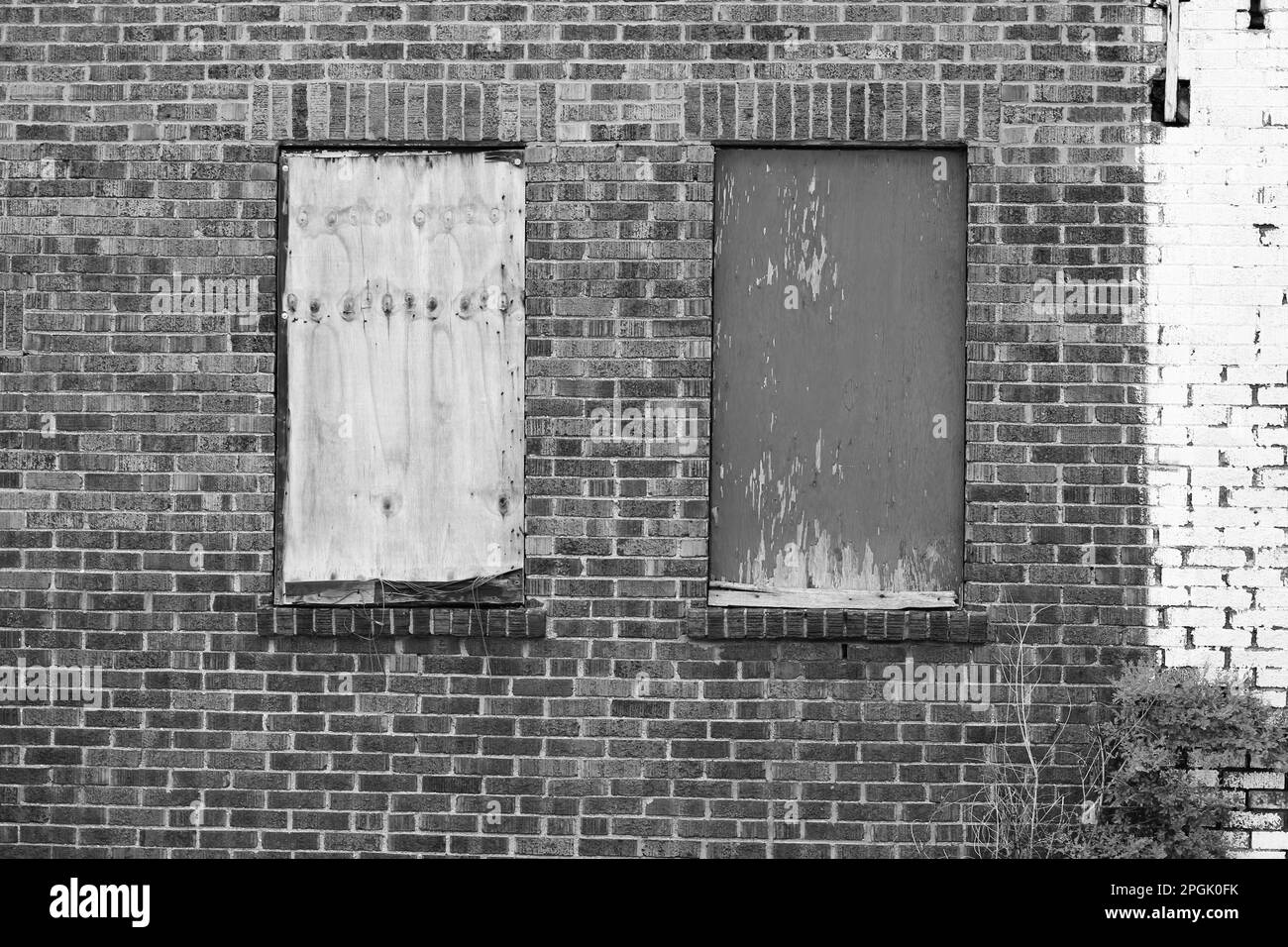 An old worn and weathered brick building blocked with plywood infill in ...