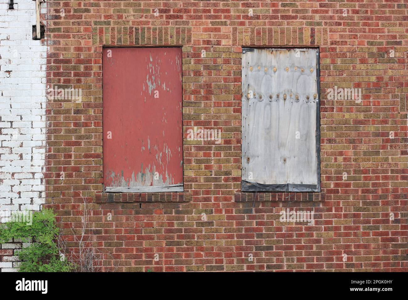 An old worn and weathered brick building blocked with plywood infill ...