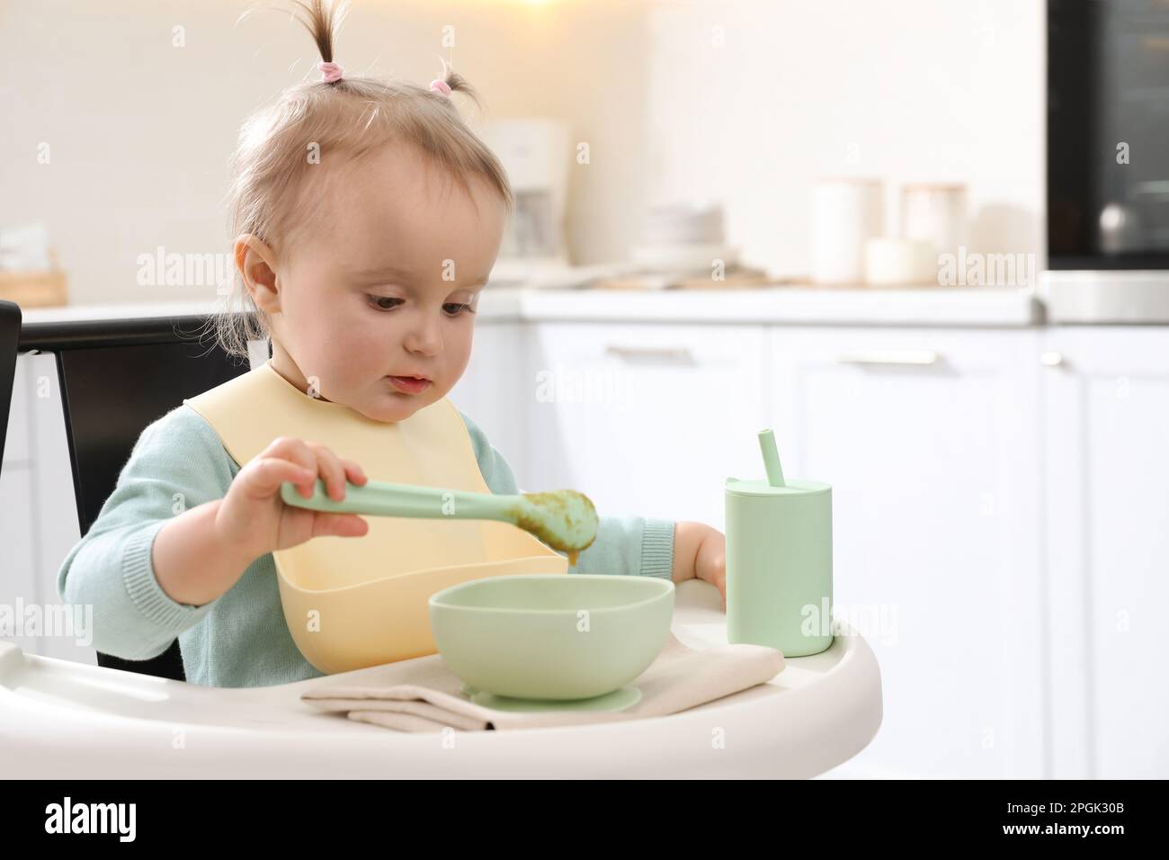 Cute little baby eating food in high chair at kitchen Stock Photo - Alamy