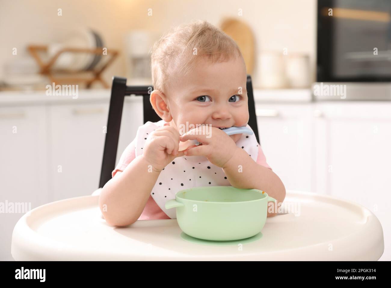 Cute little baby eating food in high chair at kitchen Stock Photo - Alamy