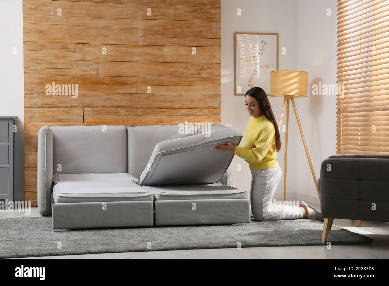 Young woman unfolding sofa into a bed in room. Modern interior Stock ...